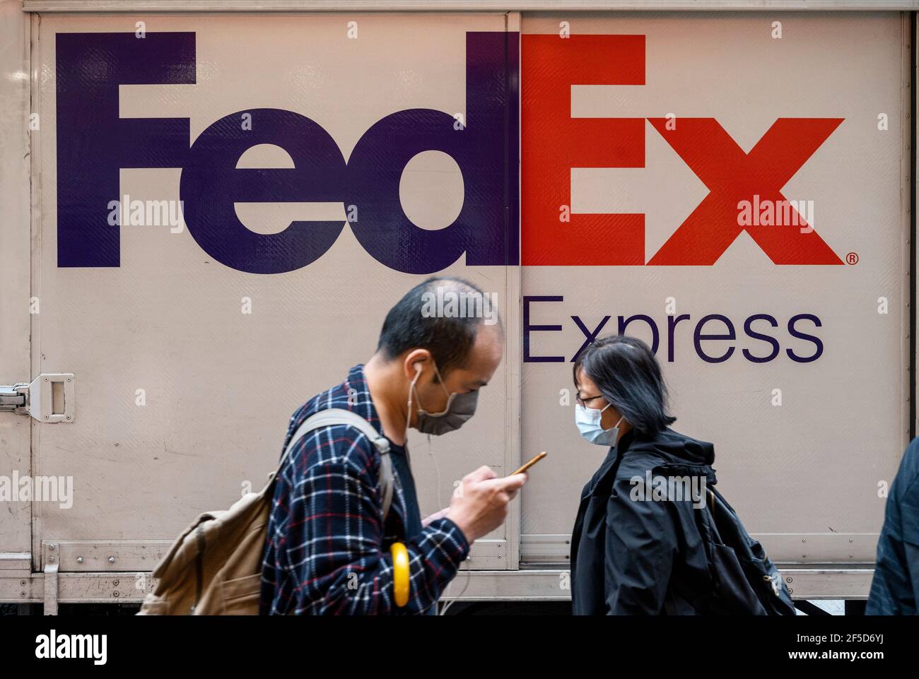 Pedestrians walk past the American FedEx Express delivery truck seen in ...