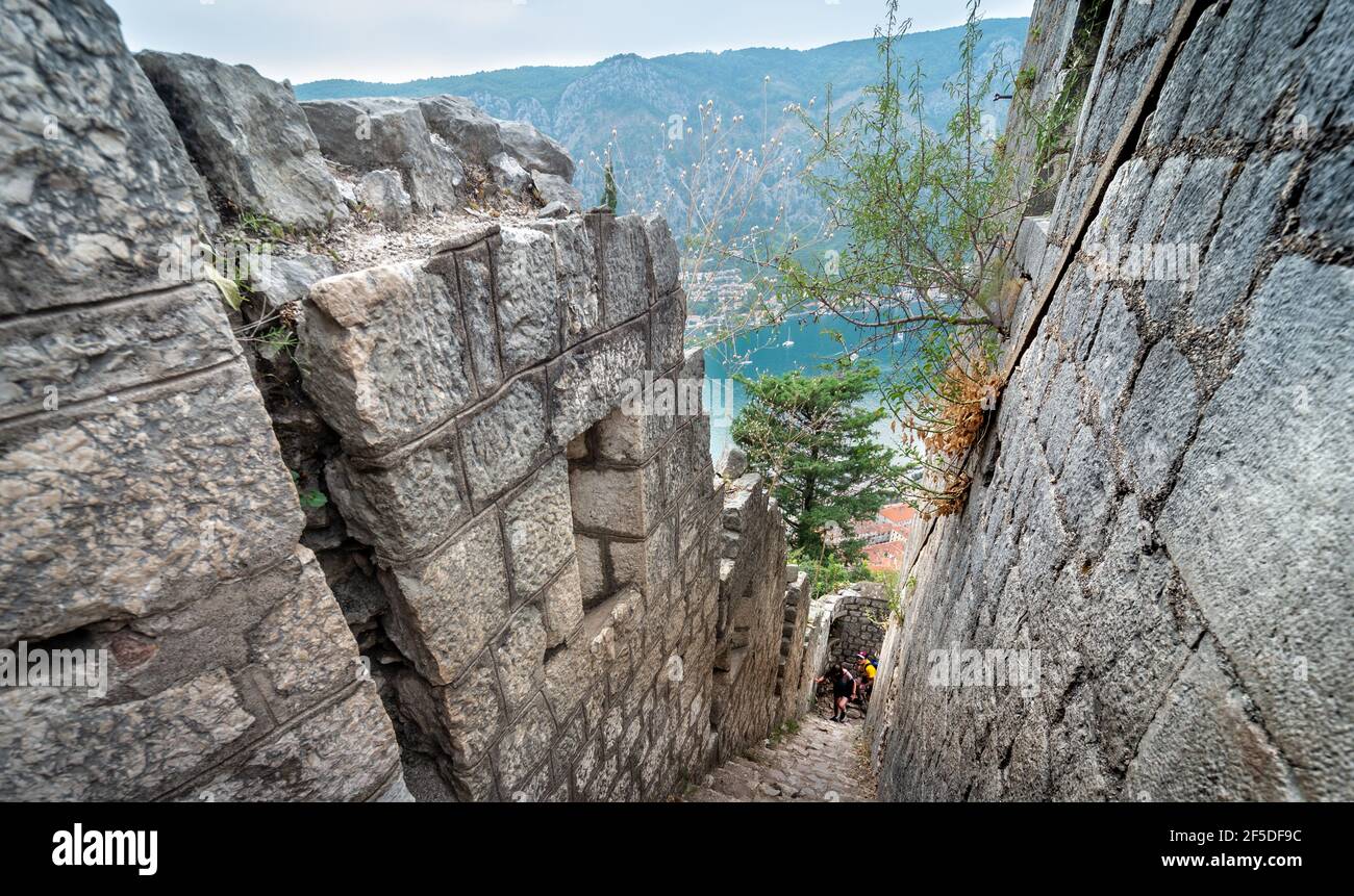 Visitors to Kotor Fortress walk up its steep crumbling steps between ...