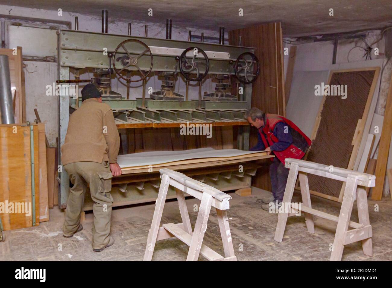 Carpenter workers are putting wooden profiles smeared with glue in the ...