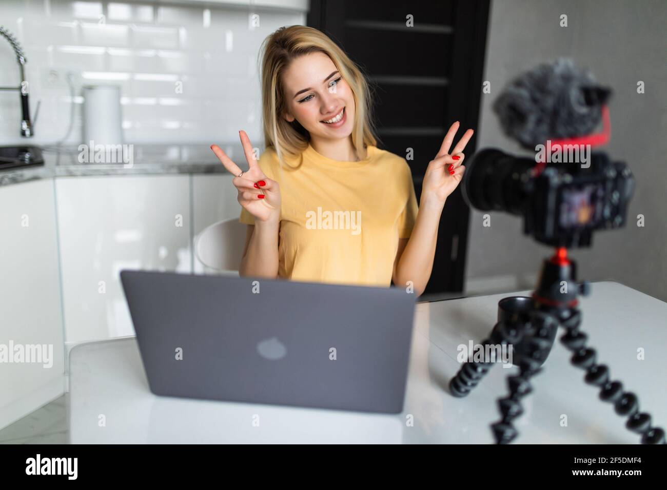 Young girl recording a video tutorial smiling and showing victory sign ...