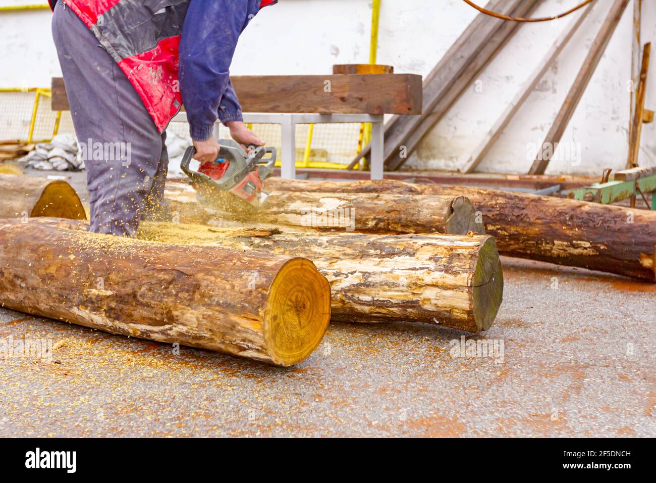 Worker at the outdoor carpentry is chopping lumbers for further ...