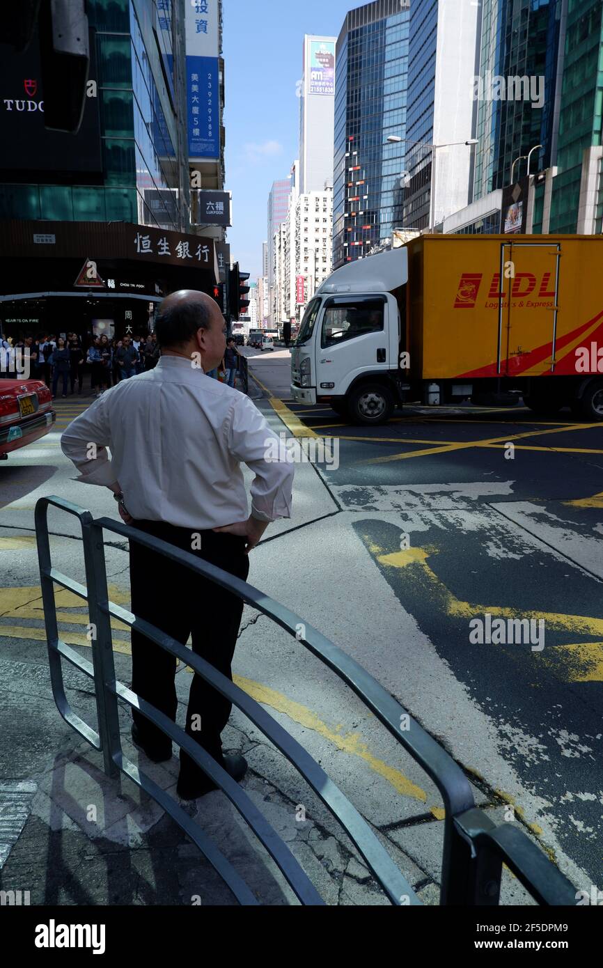 Old bald man getting ready to cross busy intersection road in Mongkok ...