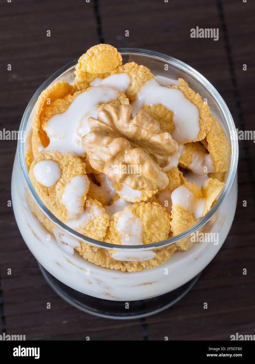 Yogurt with cornflakes and walnuts in a glass goblet Stock Photo - Alamy