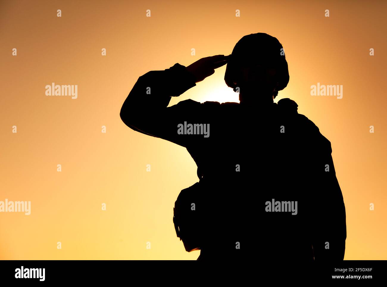 Silhouette of soldier in combat helmet and ammunition saluting on ...