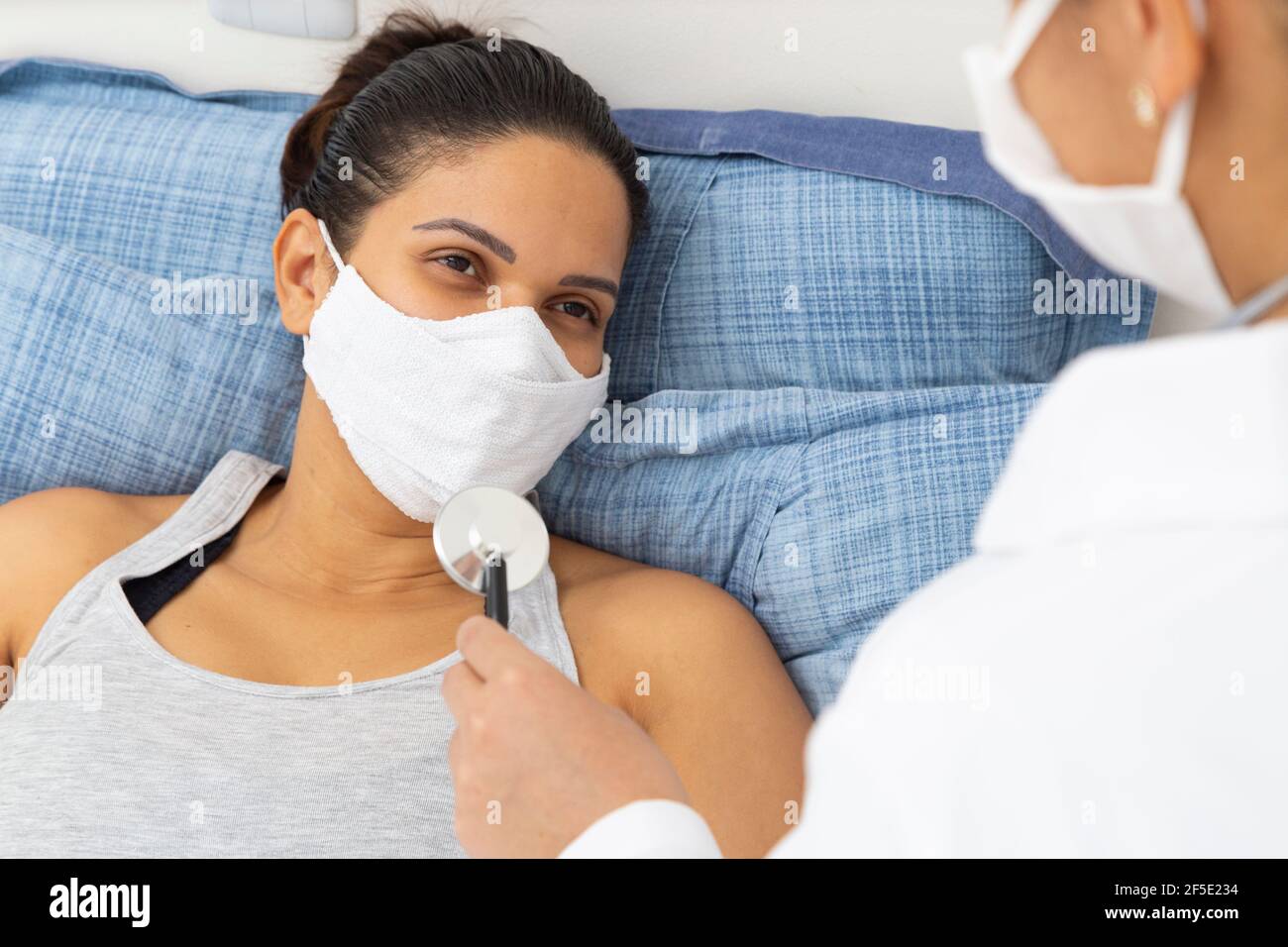 Patient in mask looking at female doctor with sick face Stock Photo - Alamy