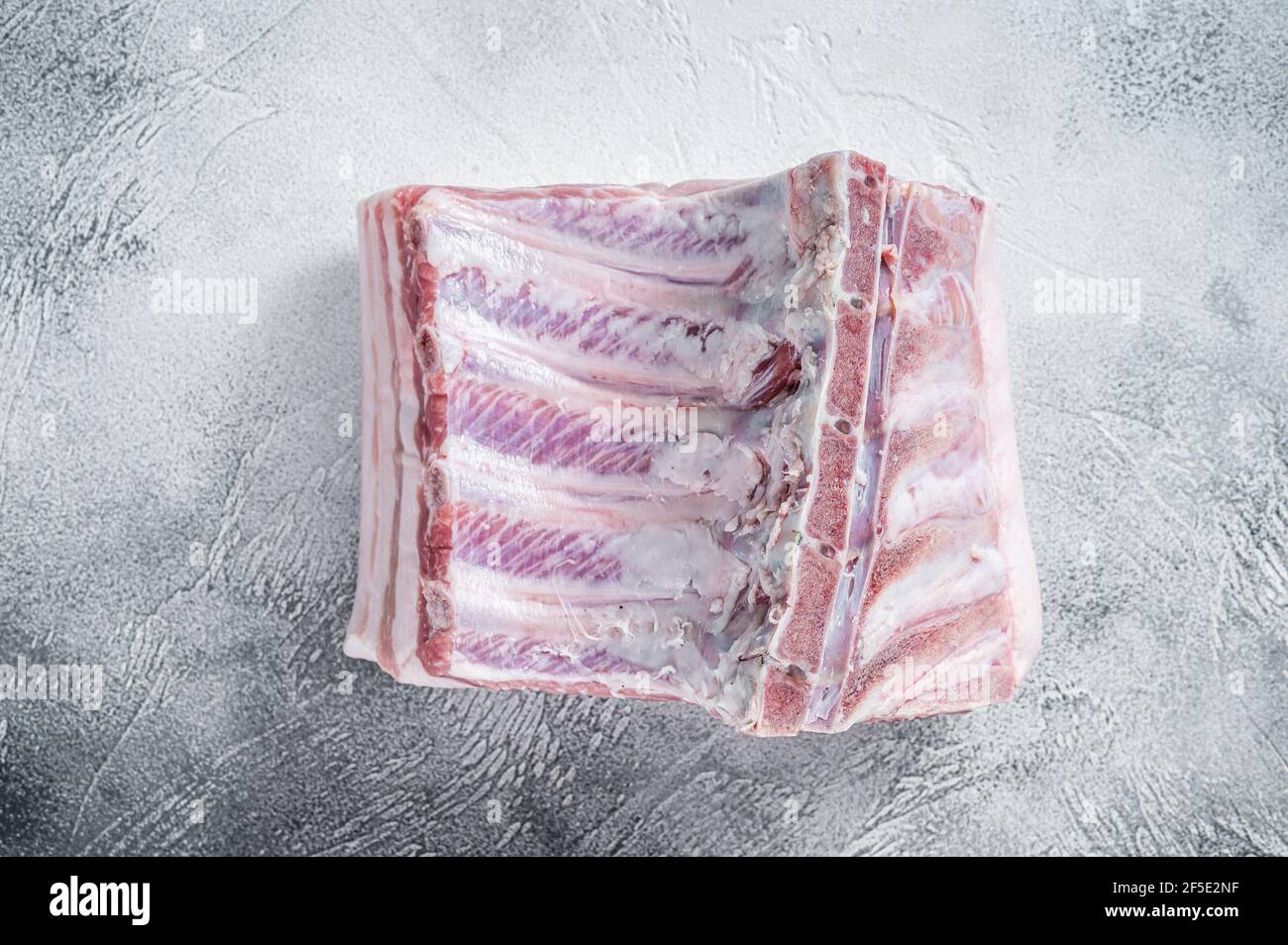 Raw whole rack of pork loin with ribs on kitchen table. White ...