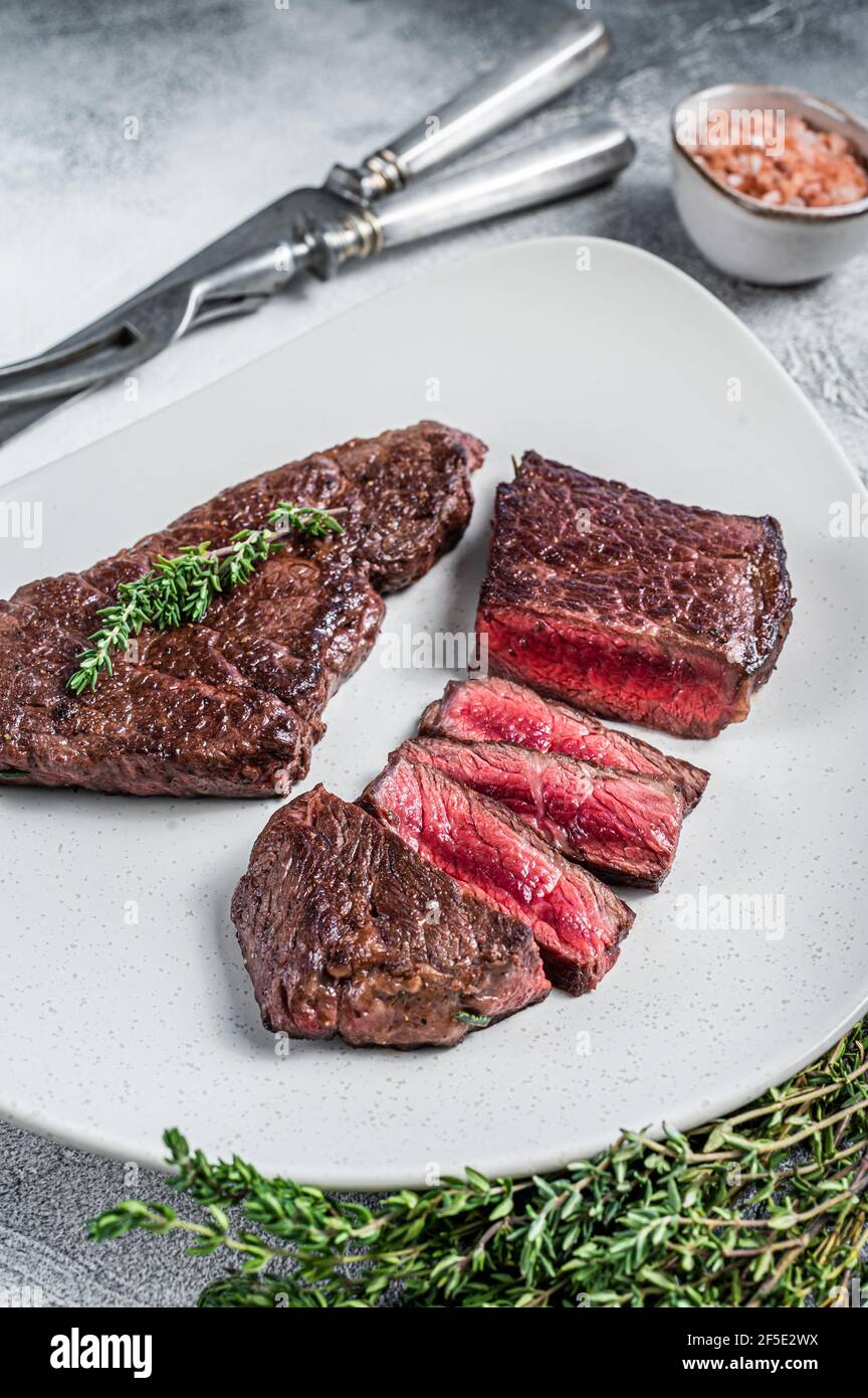 Roasted sliced rump beef meat steak on a plate with thyme. White ...