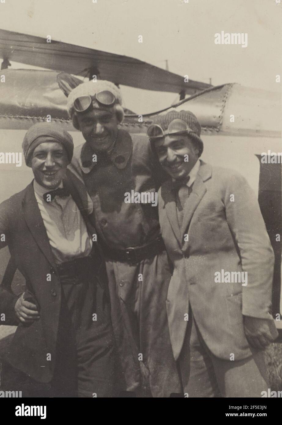 Portrait of three men smiling in front of an airplane. Fédèle Azari ...