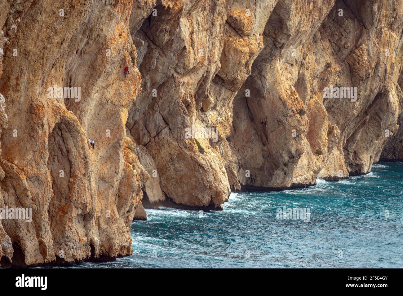 Tiny rock climbers on the huge red seacliffs of Toix at Calpe, Costa ...