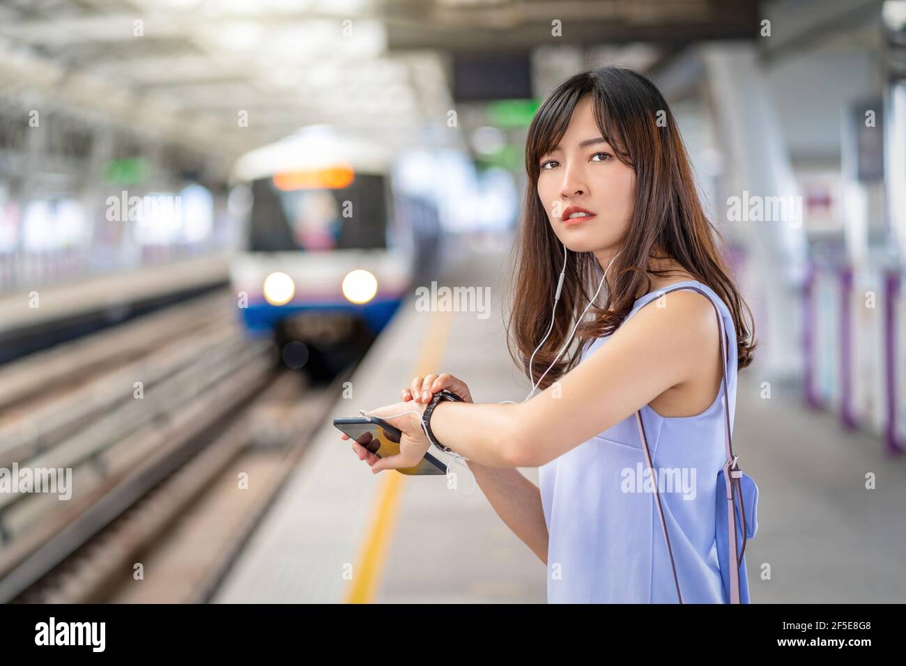 Young Asian woman passenger checking the time and waiting to her friend ...