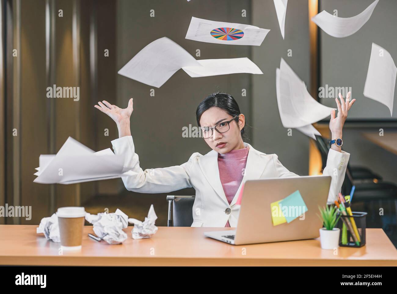 Asian businesswoman angry throwing papers over the herself in office ...