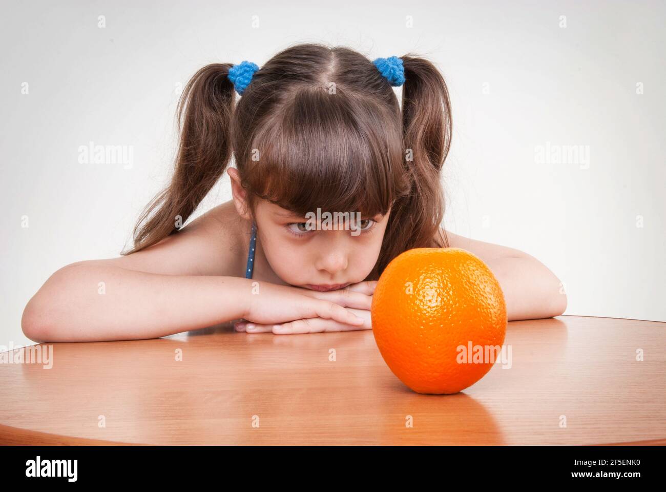 Food Allergy in a child. The girl looks sadly at the orange Stock Photo ...