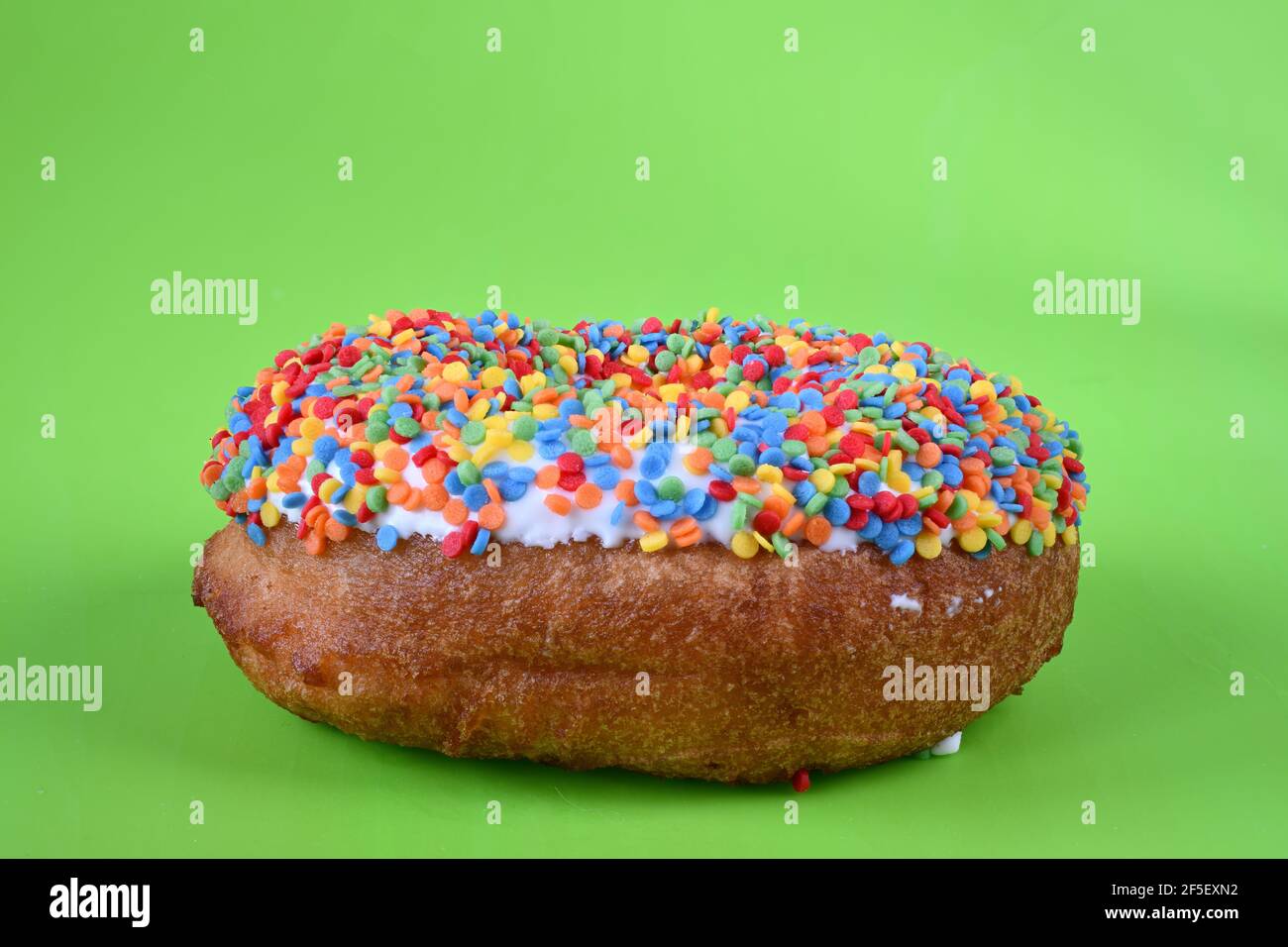 Donut in a multicolored confectionery dressing on a green background ...