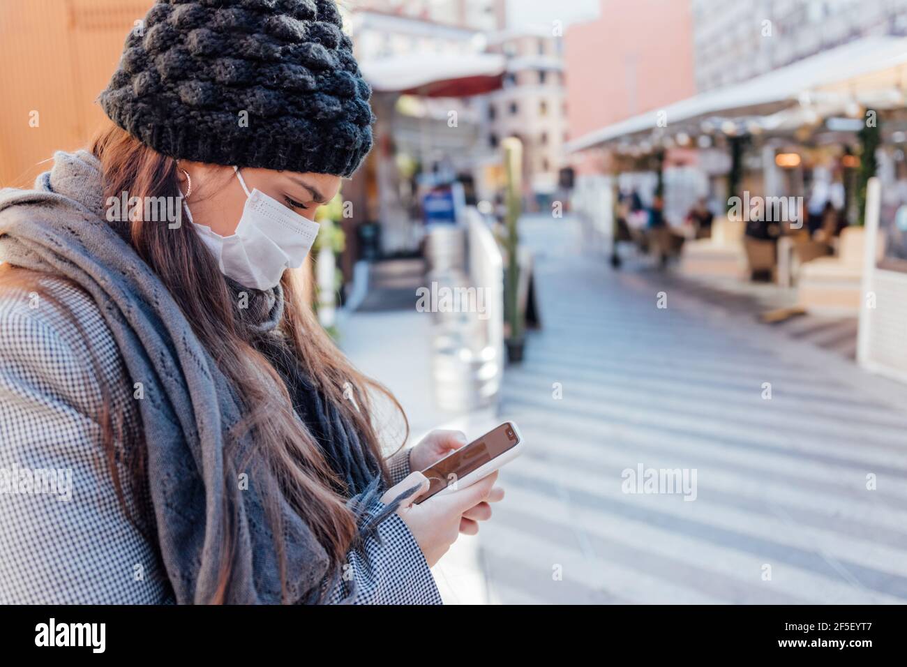 Young beautiful woman using smart phone outdoors with white protective ...