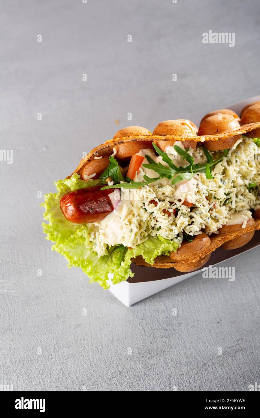 Take away wafer with sausage , bubble waffle Stock Photo - Alamy