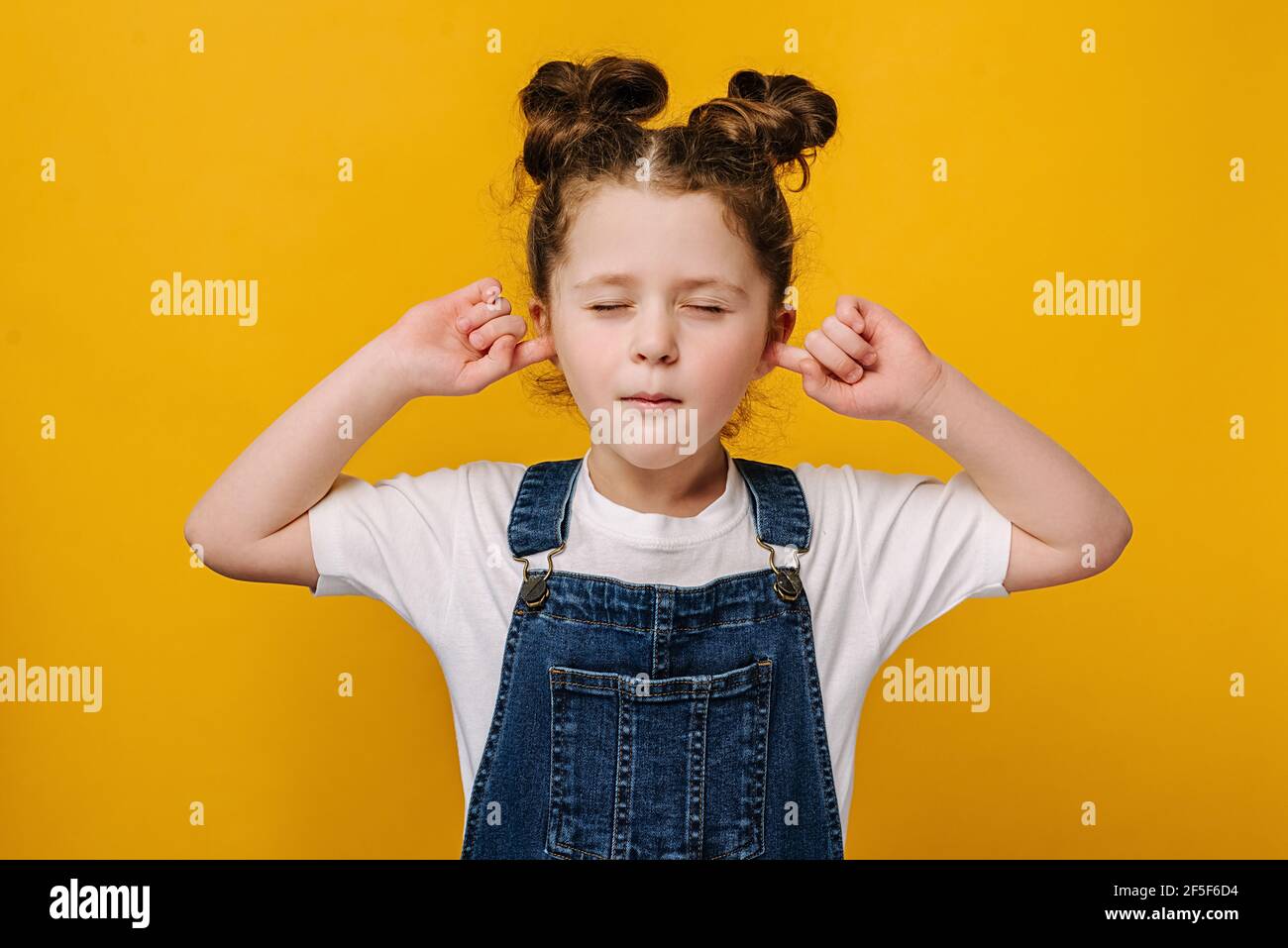 Unhappy little girl kid with having discontent look plugging her ears ...