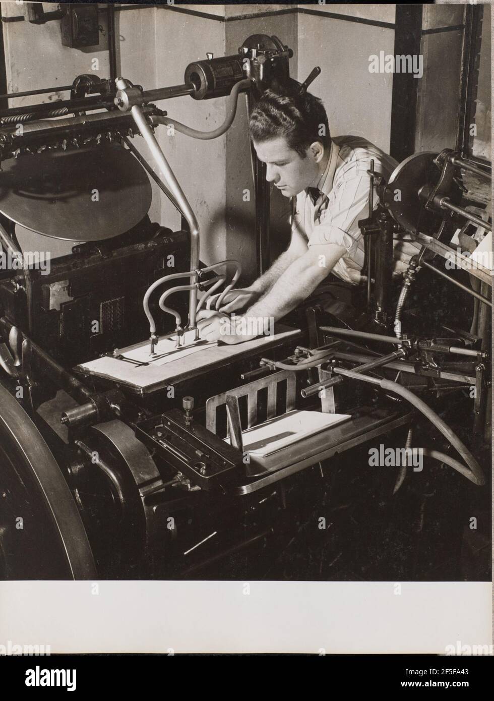 Man adjusts tubes on a printing press. Arnold Eagle (American, 1909 ...