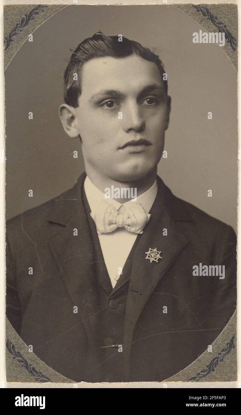 Unidentified young man wearing a white bow tie and a pin on his lapel ...