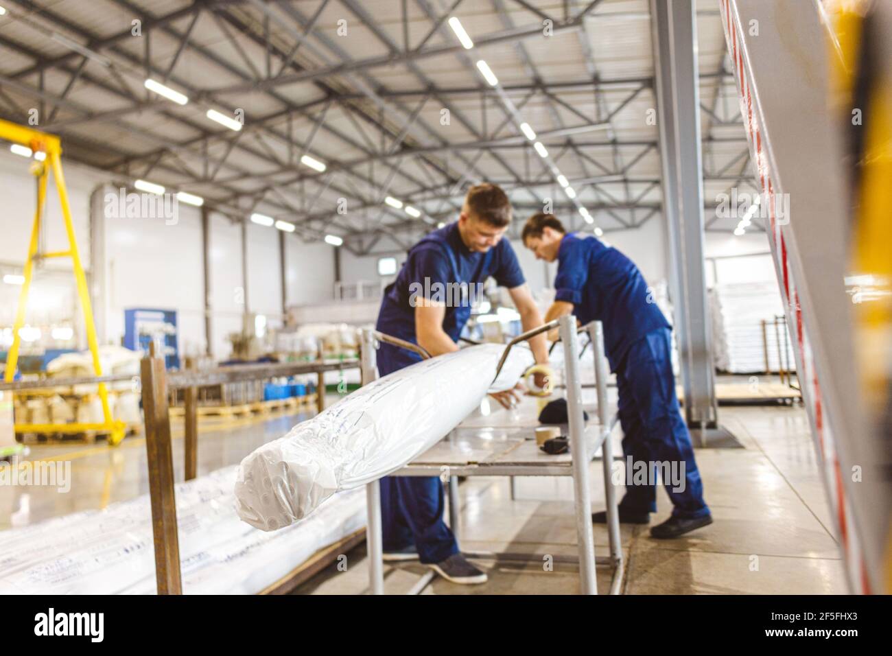 Professional workers in protective overalls pack and pack products ...