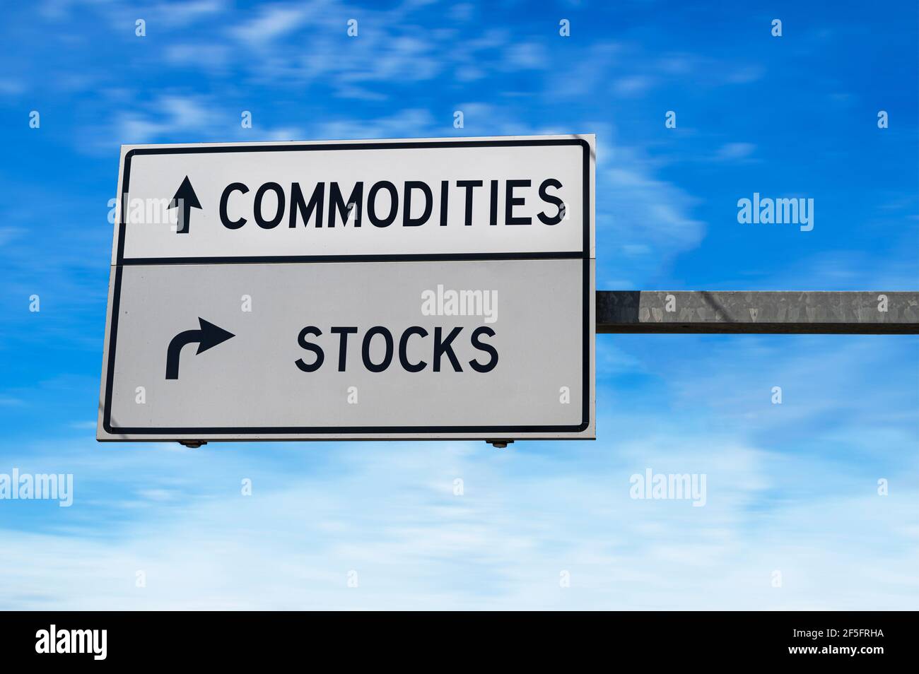 Road sign with words commodities and stocks. White two street signs ...