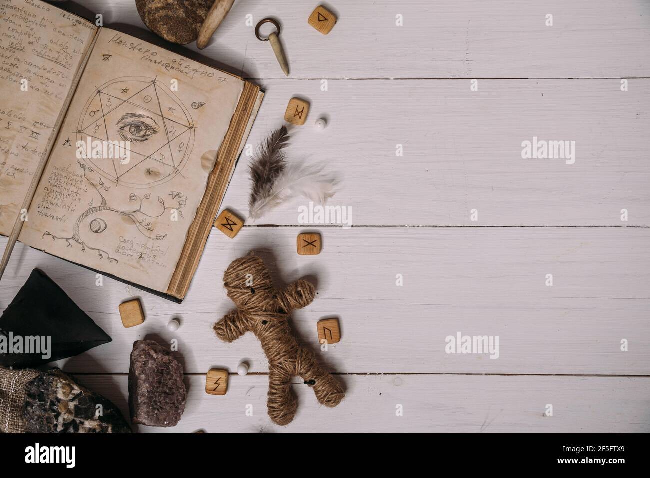 A voodoo doll made of rope lies with old book grimoire, surrounded by ...