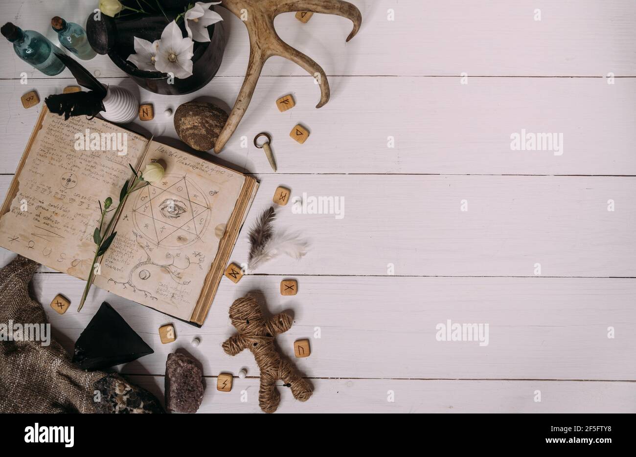 A voodoo doll made of rope lies with old book grimoire, surrounded by ...