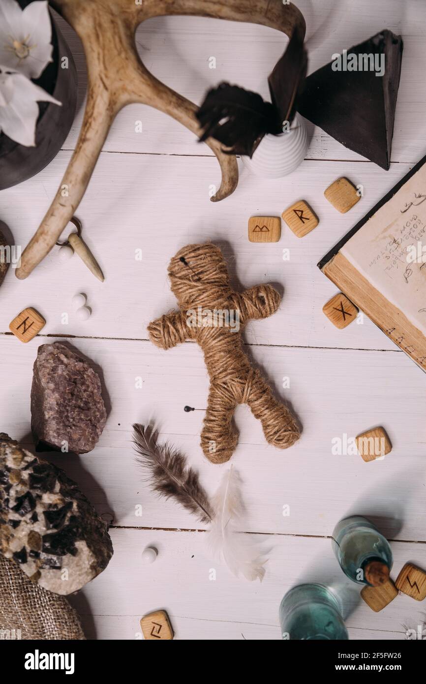 A voodoo doll made of rope lies with old book grimoire, surrounded by ...