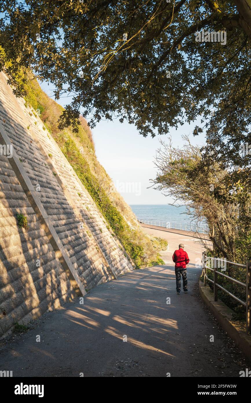 A man walking down the chine to the lower promenade and sea in ...