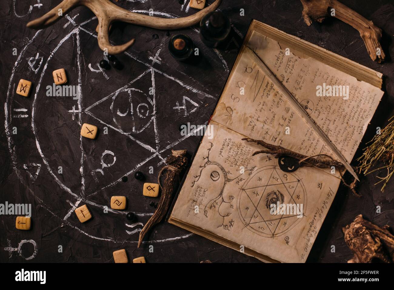 Open old book with magic spells, runes, black candles on witch table ...