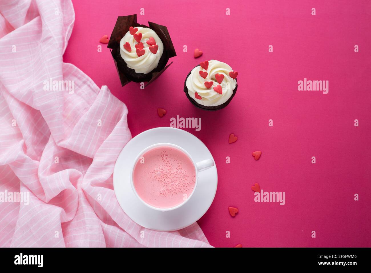Cupcake decorated with hearts on pink background and cup with pink ...