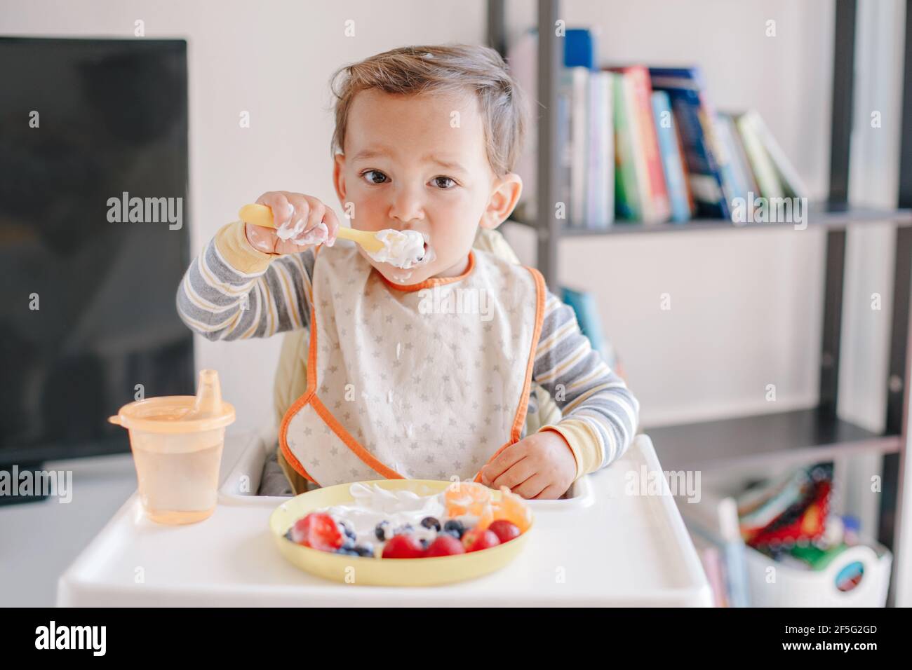 Cute Caucasian baby boy eating ripe berries and fruits with yogurt ...