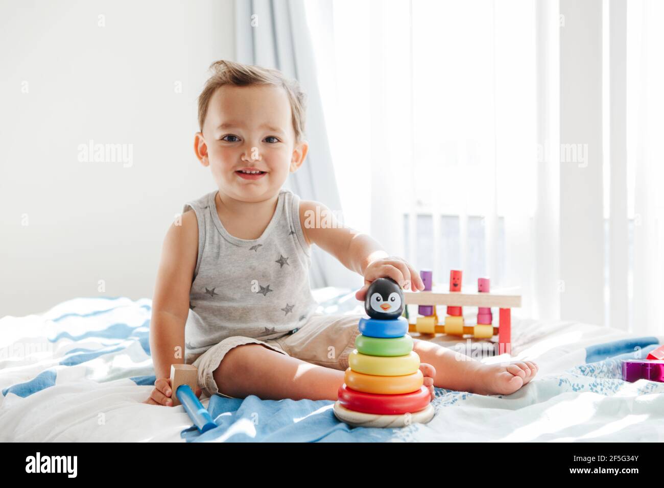 Cute baby toddler playing with learning toy pyramid stacking blocks at ...