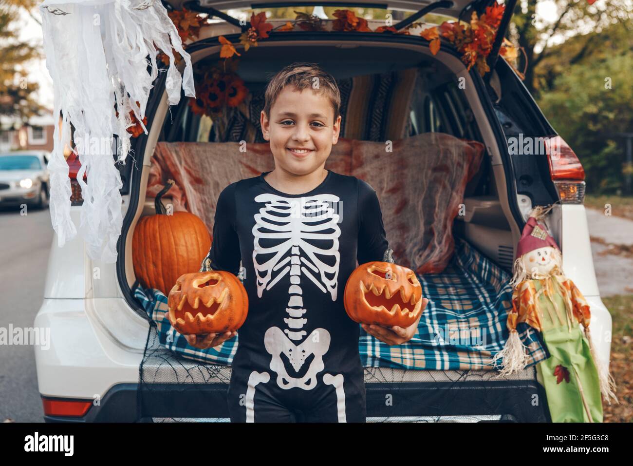 Trick or trunk. Boy child with red carved pumpkins celebrating ...