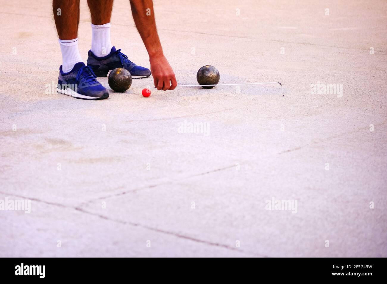 Petanque game, man measures distance between balls Stock Photo - Alamy