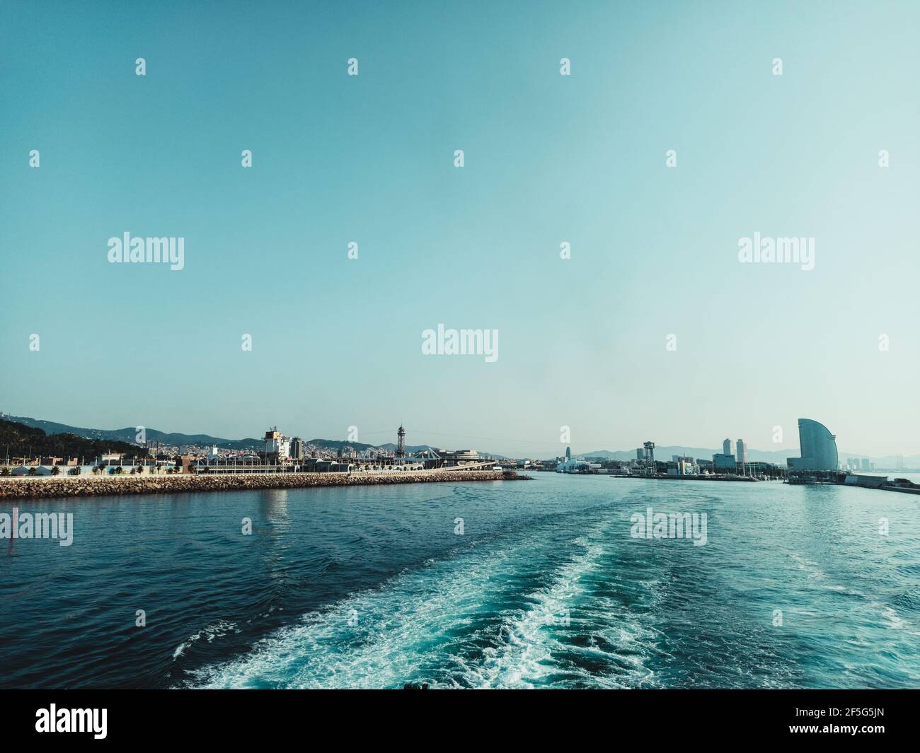 Wave wake from sailing ship with Port and Ropeway of Barcelona, Spain ...