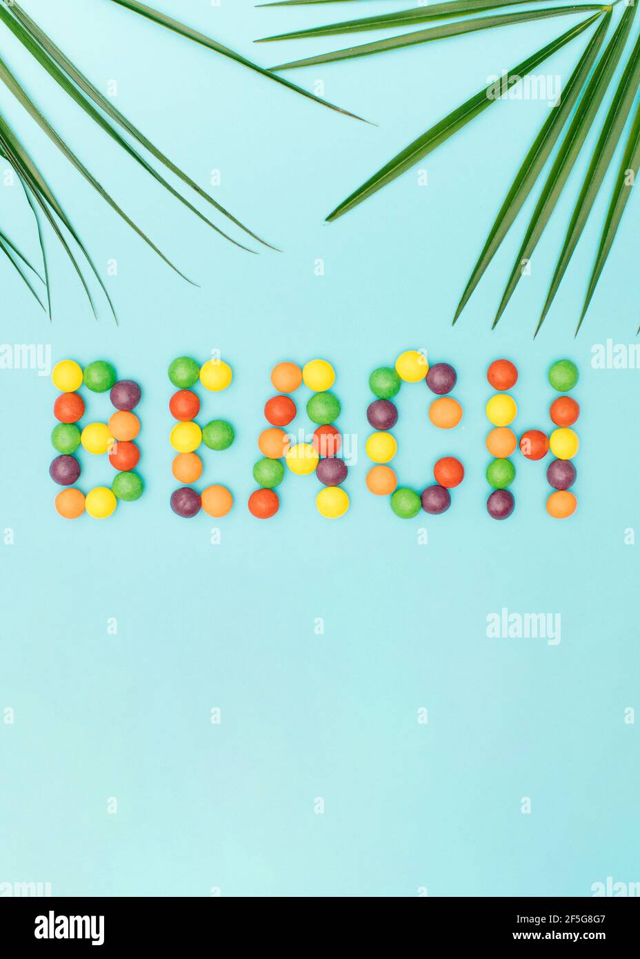 Beach word made from colored balls and palm leaves on a blue background ...