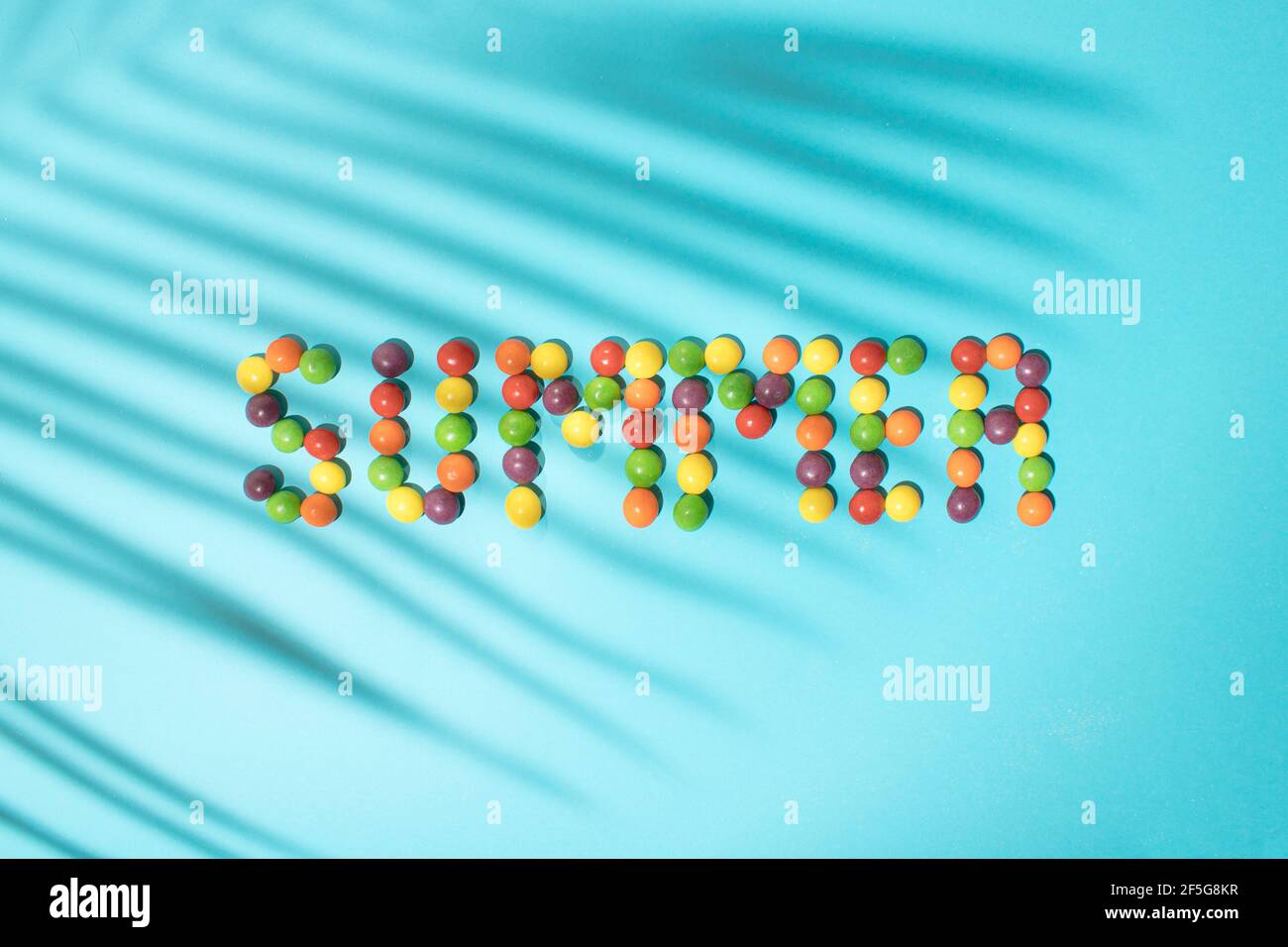 Summer word made from colored balls on a blue background with palm leaf ...