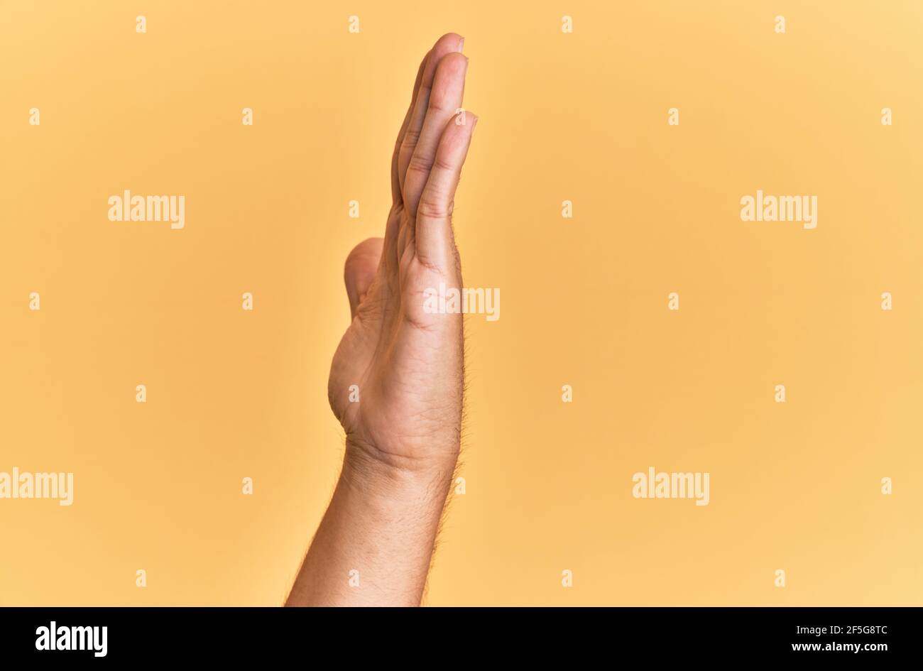 Arm and hand of caucasian man over yellow isolated background showing ...
