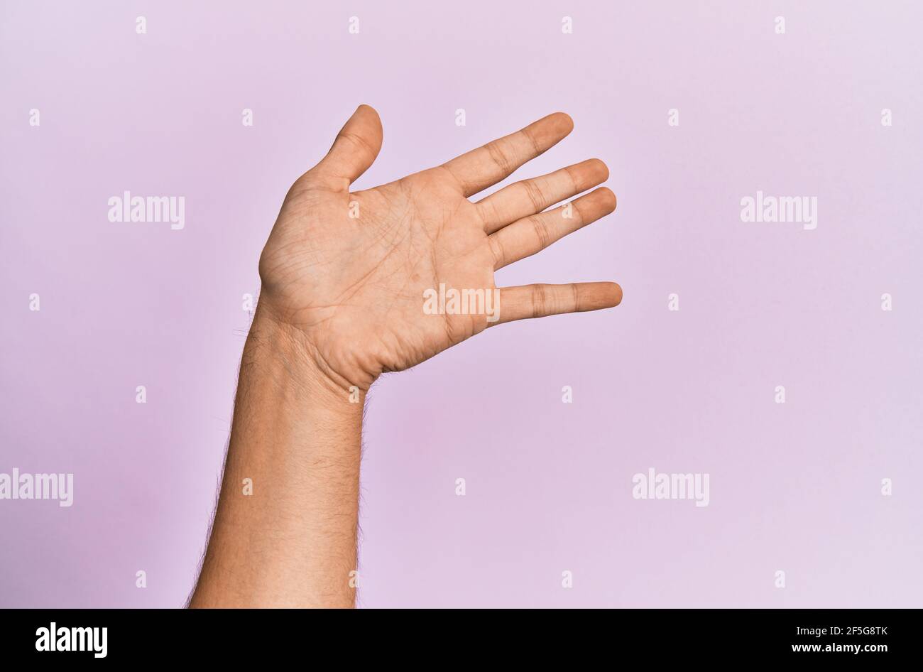 Arm and hand of caucasian young man over pink isolated background ...
