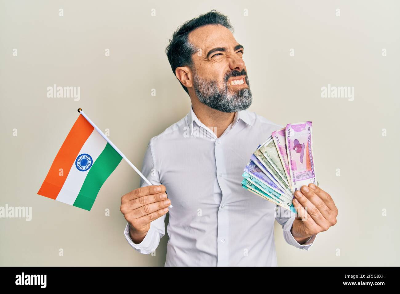 Middle age man with beard and grey hair holding india flag and rupee ...