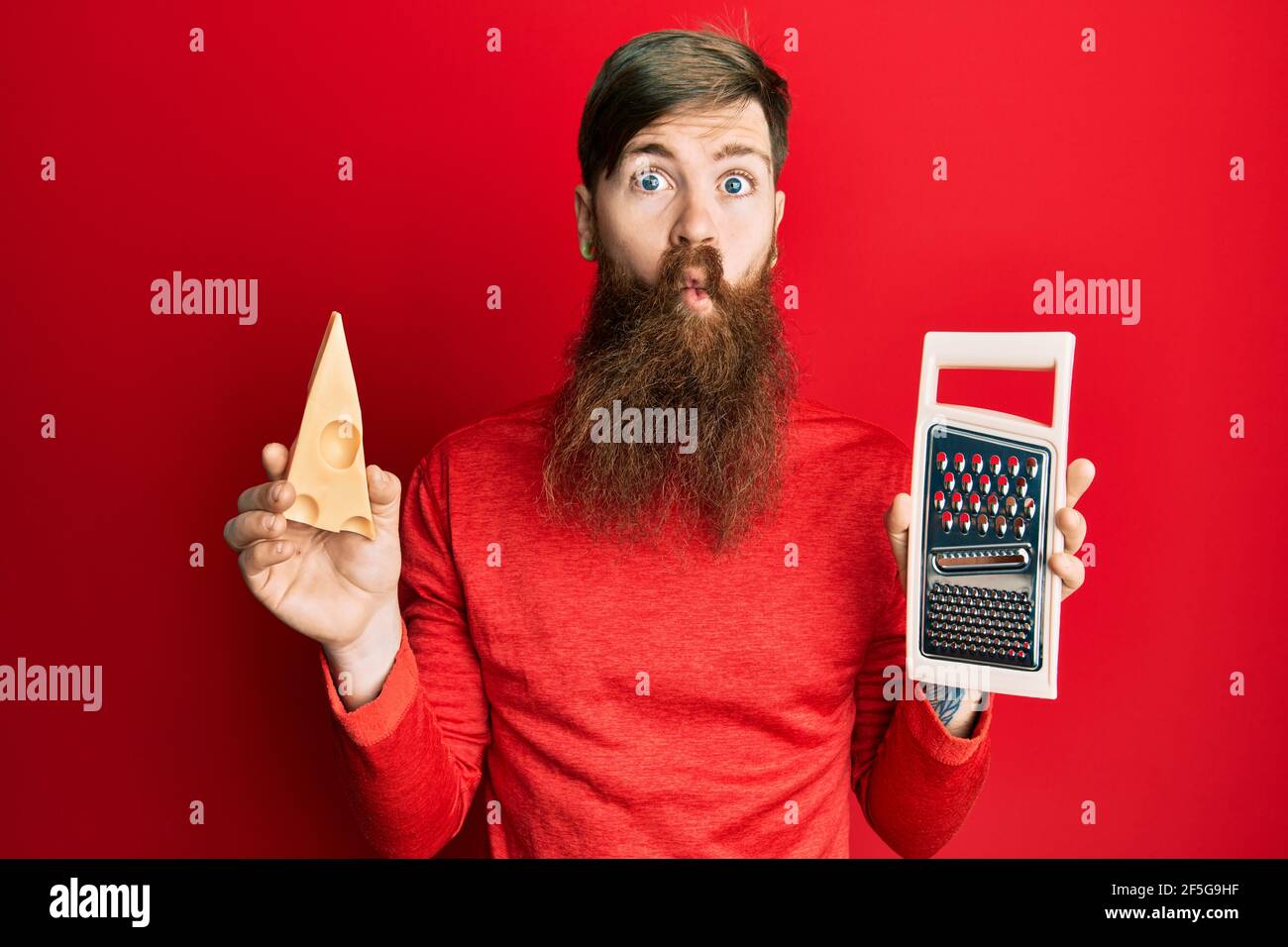 Redhead man with long beard holding grater and cheese making fish face ...