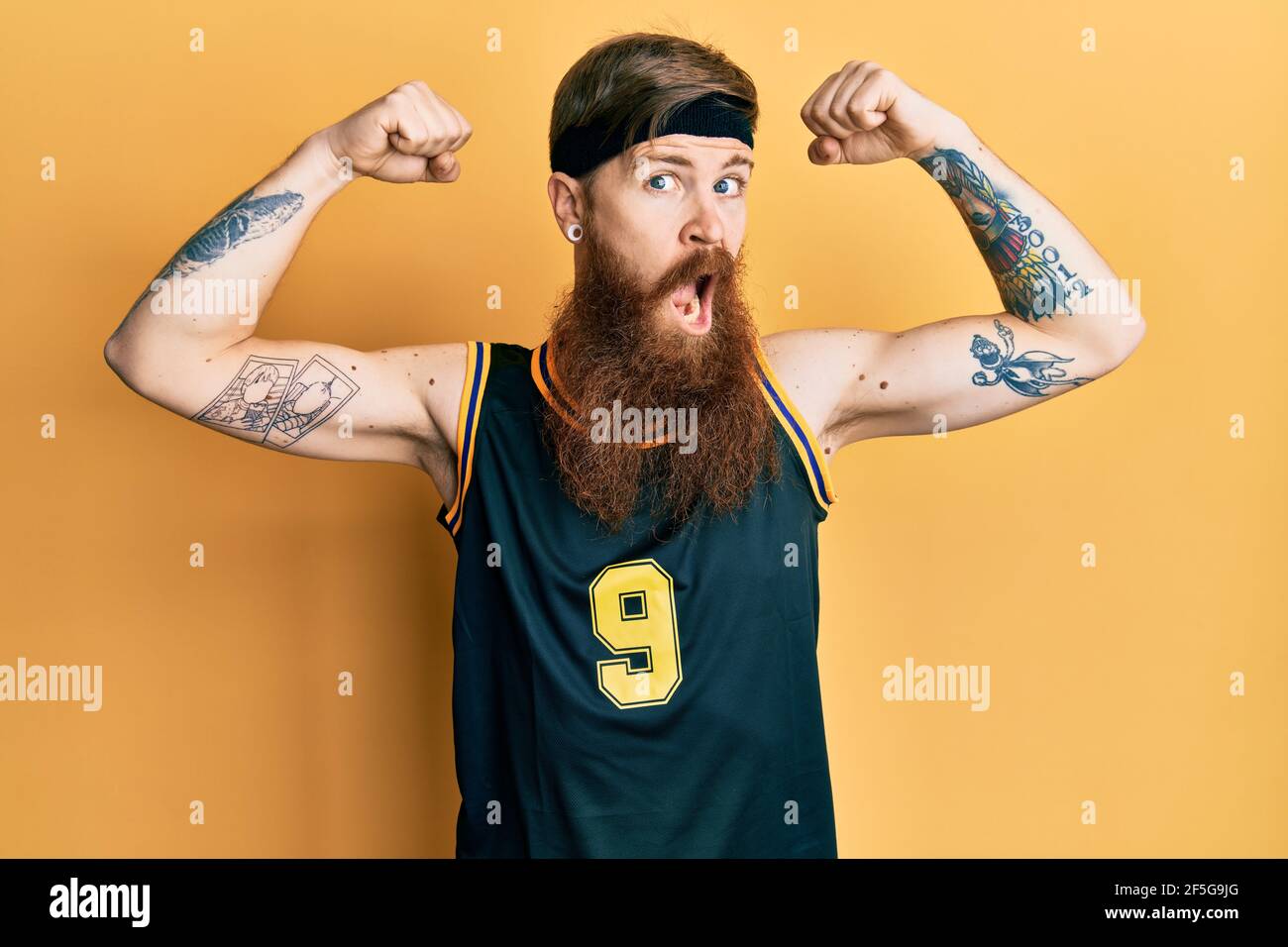 Redhead man with long beard wearing basketball uniform showing muscles ...