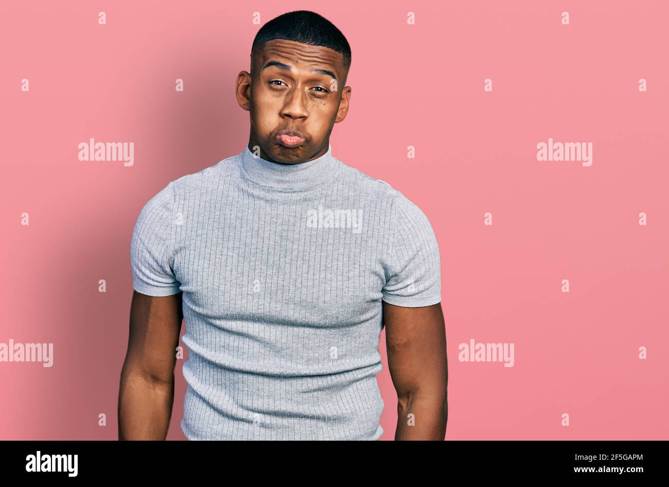 Young black man wearing casual t shirt puffing cheeks with funny face ...