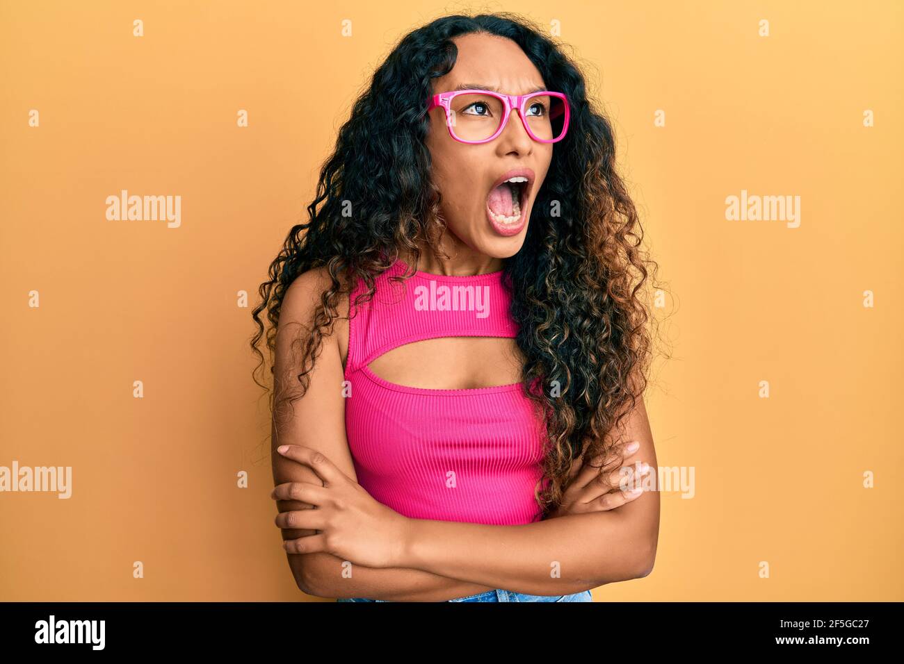 Young latin woman wearing casual clothes and glasses angry and mad ...