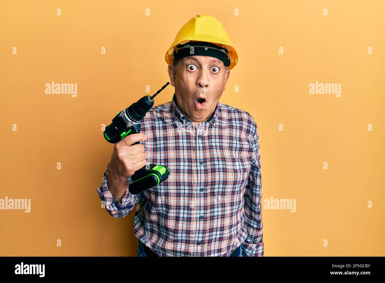 Handsome senior man with grey hair holding electric screwdriver wearing ...