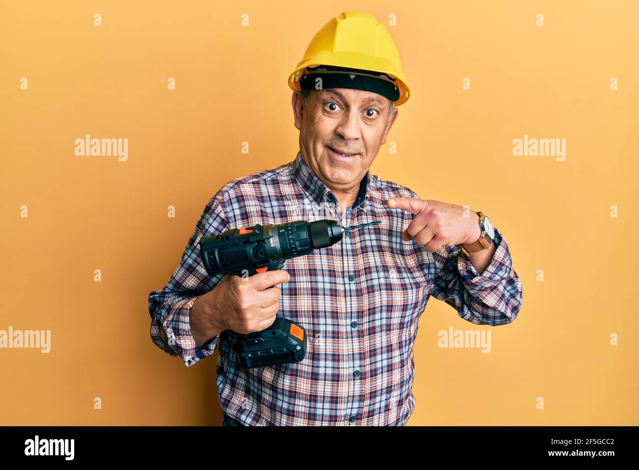 Handsome senior man with grey hair holding screwdriver wearing hardhat ...
