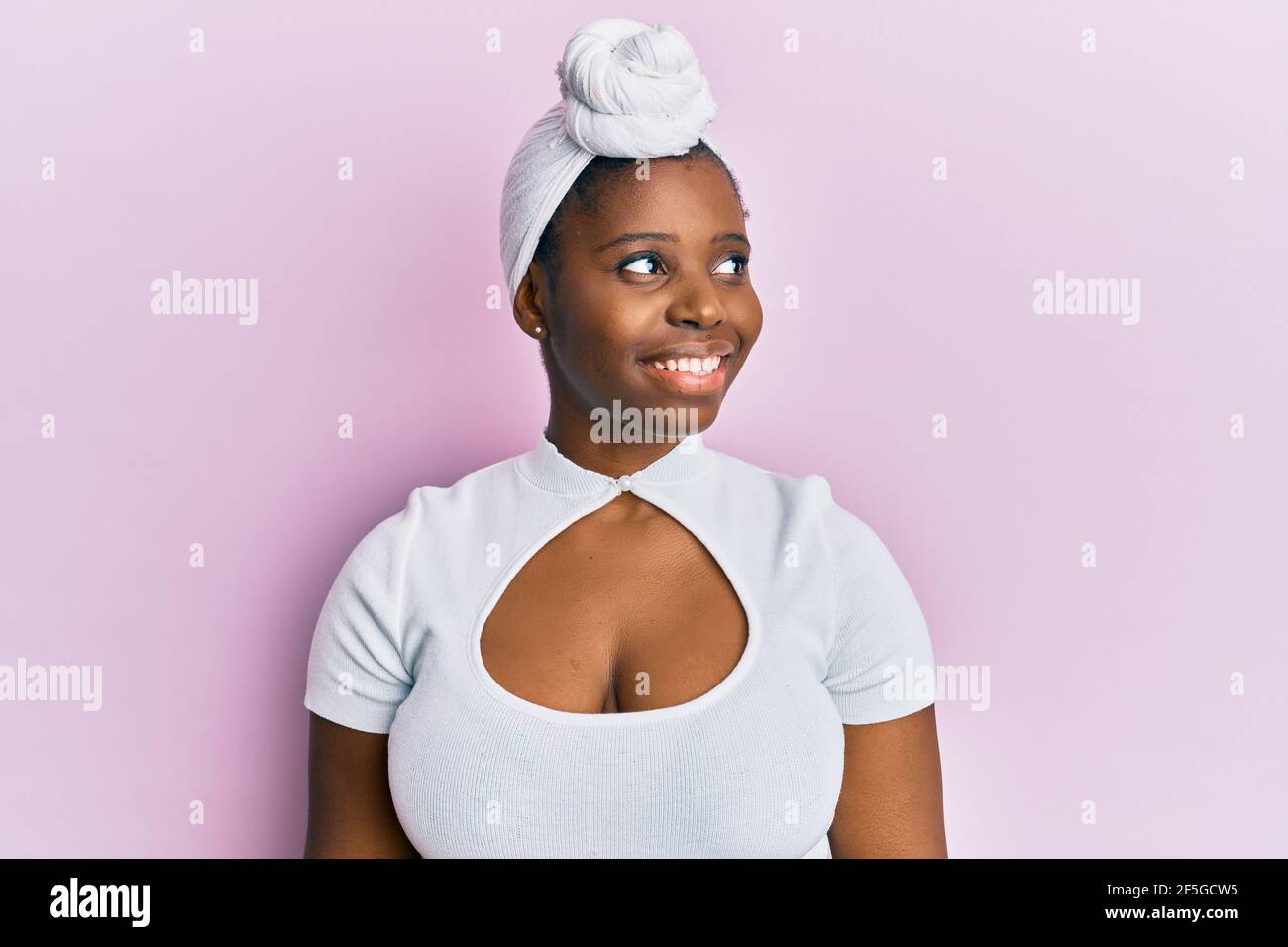 Young african woman wearing hair turban over pink background looking to ...
