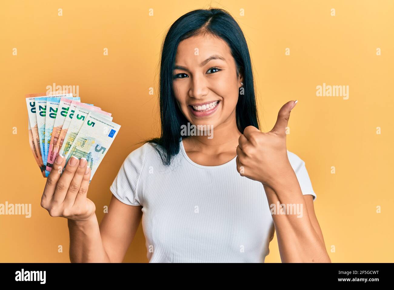 Beautiful hispanic woman holding euro banknotes smiling happy and ...