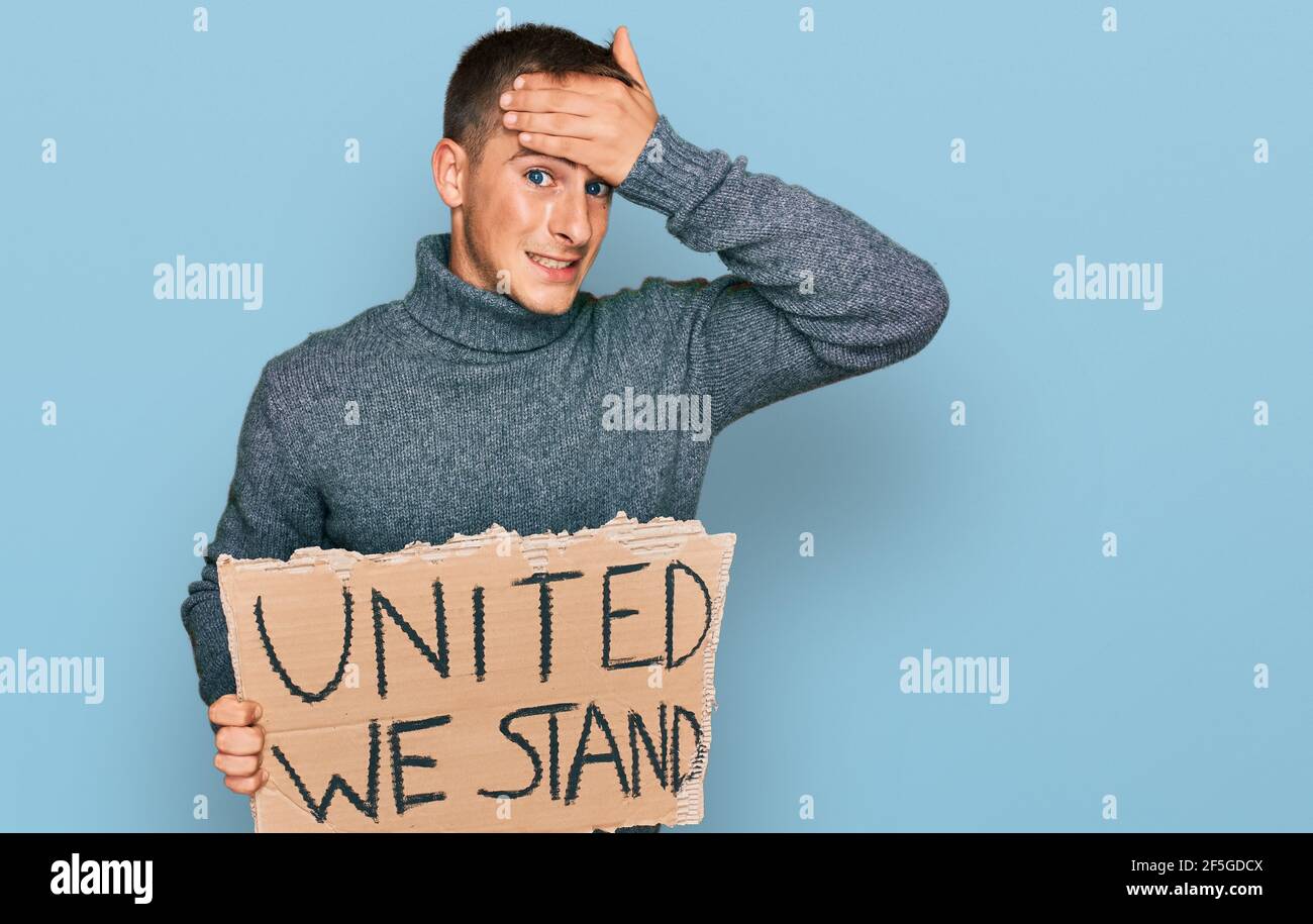 Young blond man holding united we stand banner stressed and frustrated ...