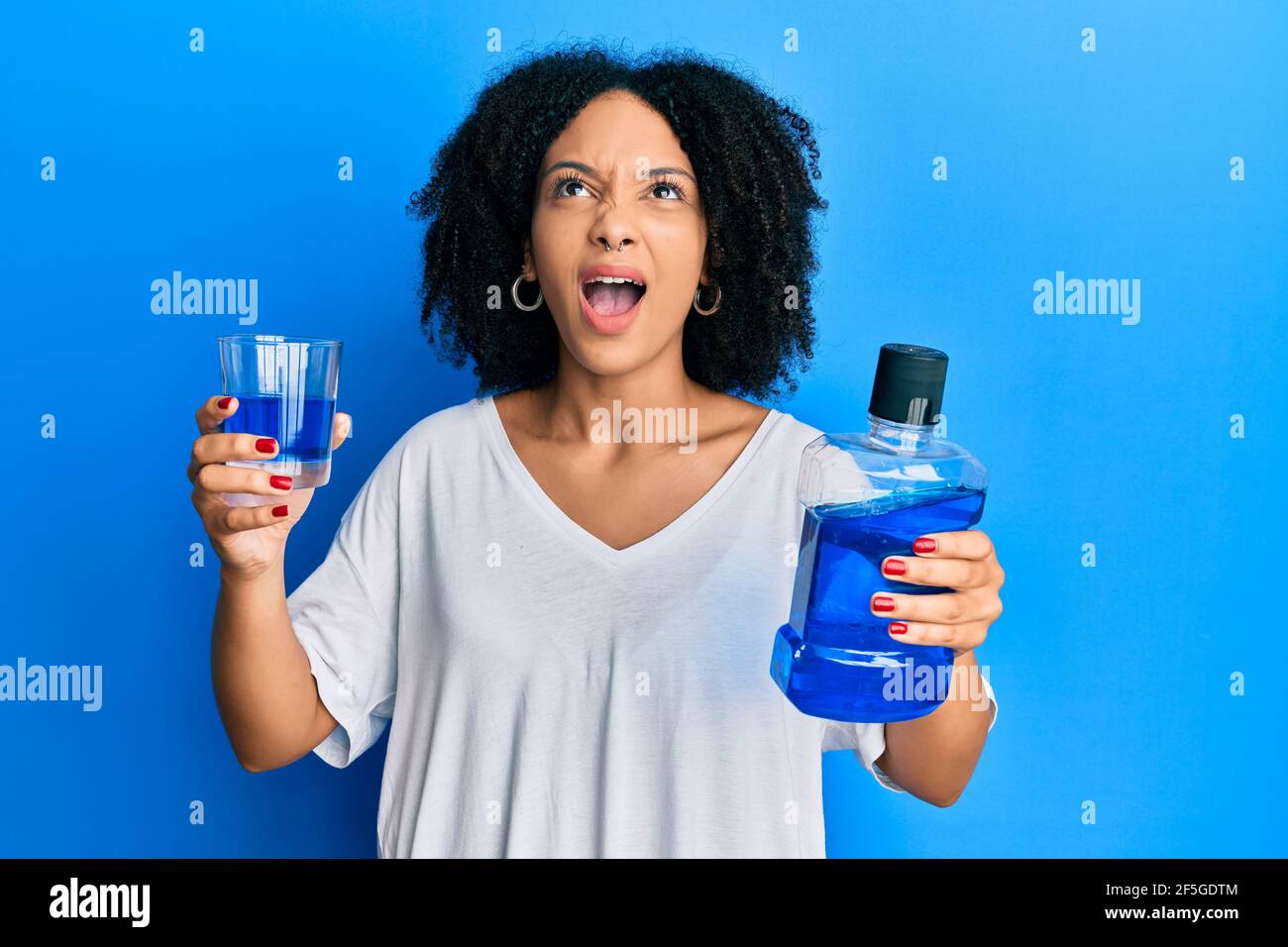 Young african american girl holding mouthwash for fresh breath angry ...